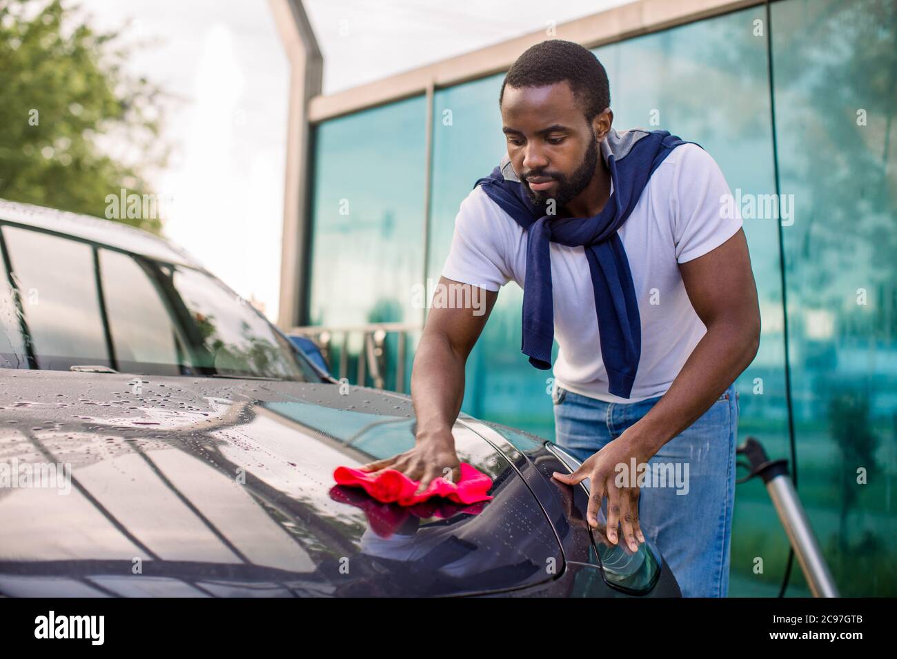 Horizontal shot of a young African American man cleaning the hood on ...