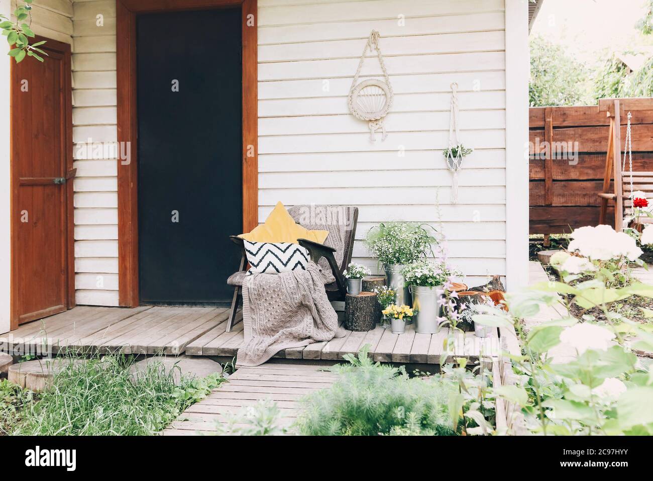 Entrance of wooden country house with lush plants in courtyard on sunny ...