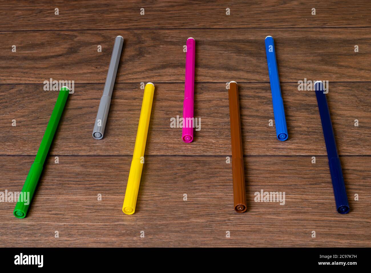 A lot of multi-colored colorful vibrant felt-tip pens on a brown wooden ...