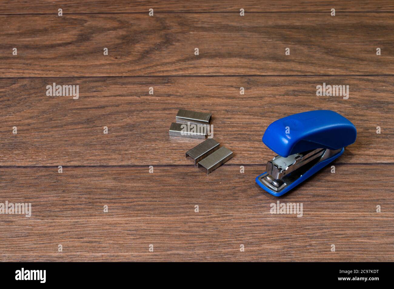 Blue stapler and staples on a brown wooden background. For business and ...
