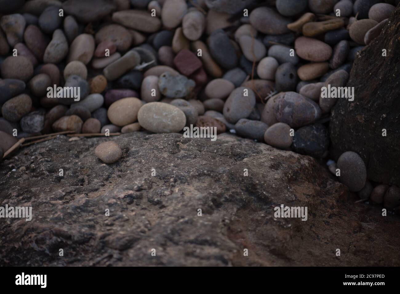 Rock surface and a blurry background of pebbles Stock Photo - Alamy