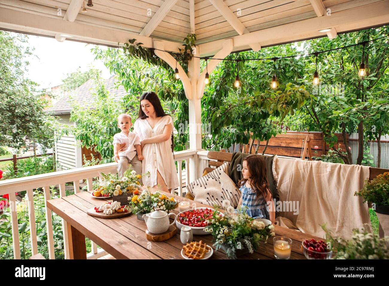 Smiling woman sitting on bench with adorable siblings at wooden table ...