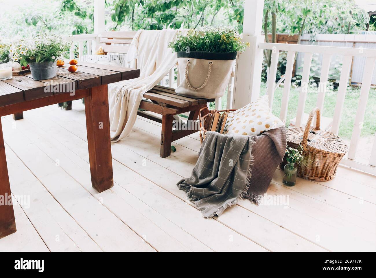 High angle of wooden terrace of house with bench and bunch of flowers ...