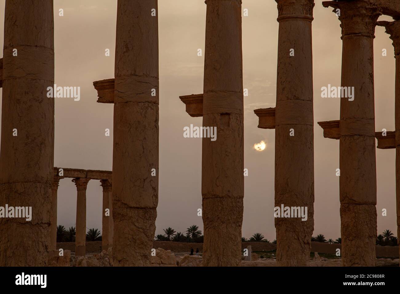 Sun rises between the stone pillars of the ancient ruins in Palmyra ...