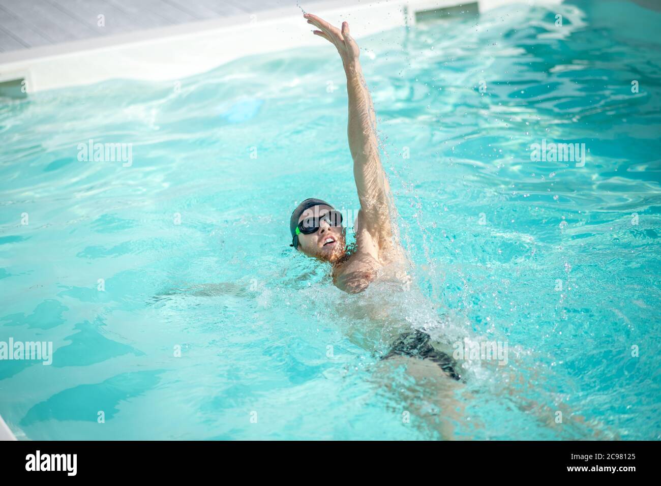 Swimmer swimming on his back arm straight raised up Stock Photo - Alamy