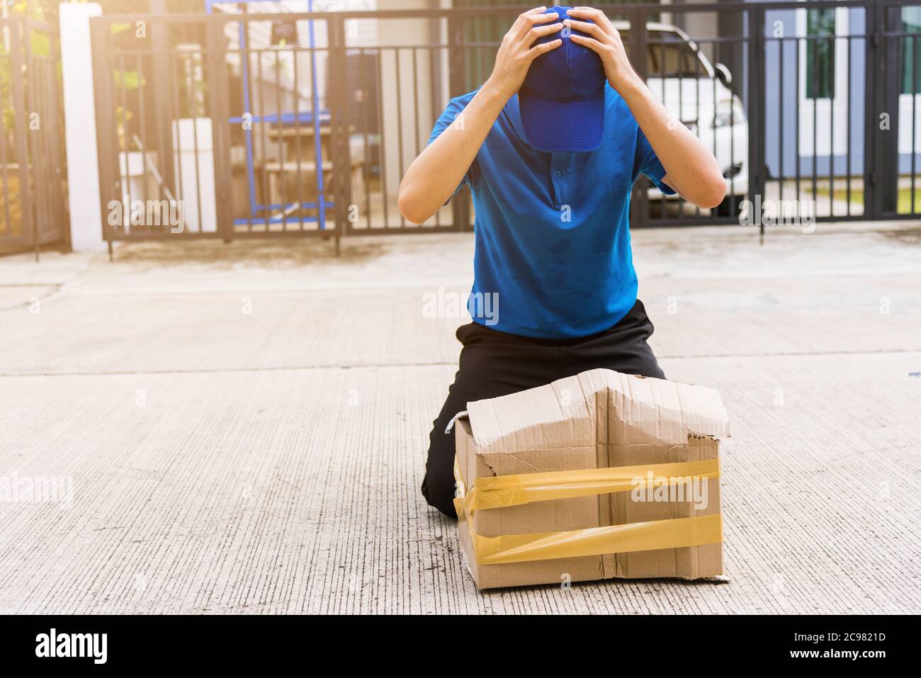 Asian young delivery man in blue uniform he emotional falling courier ...