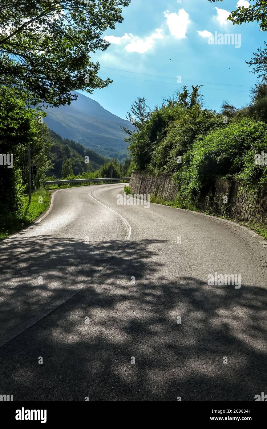 S-curve of asphalt road on sunny day, with tree shadow on the track ...