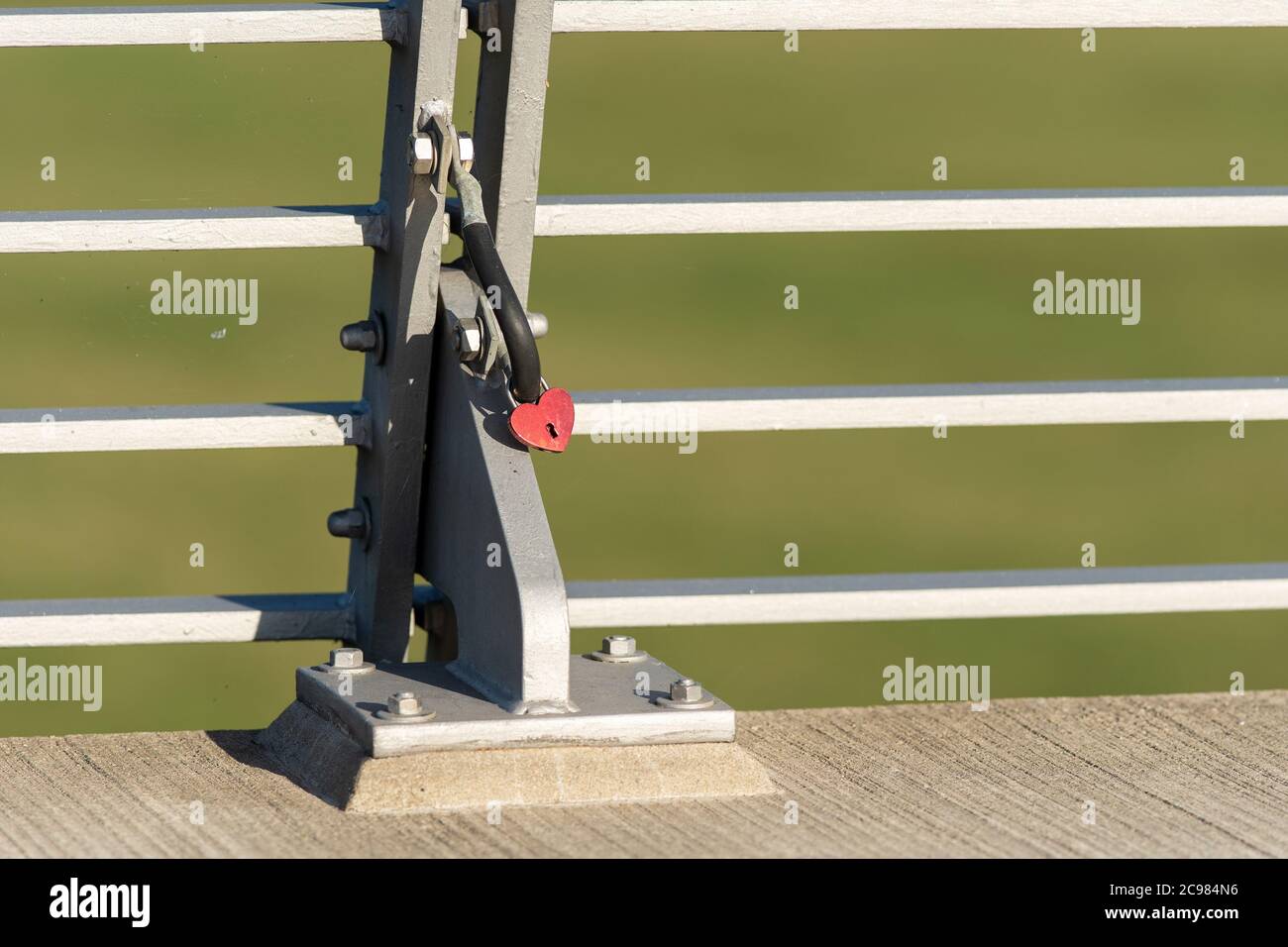 Red lock hanging on a bridge railing Stock Photo - Alamy