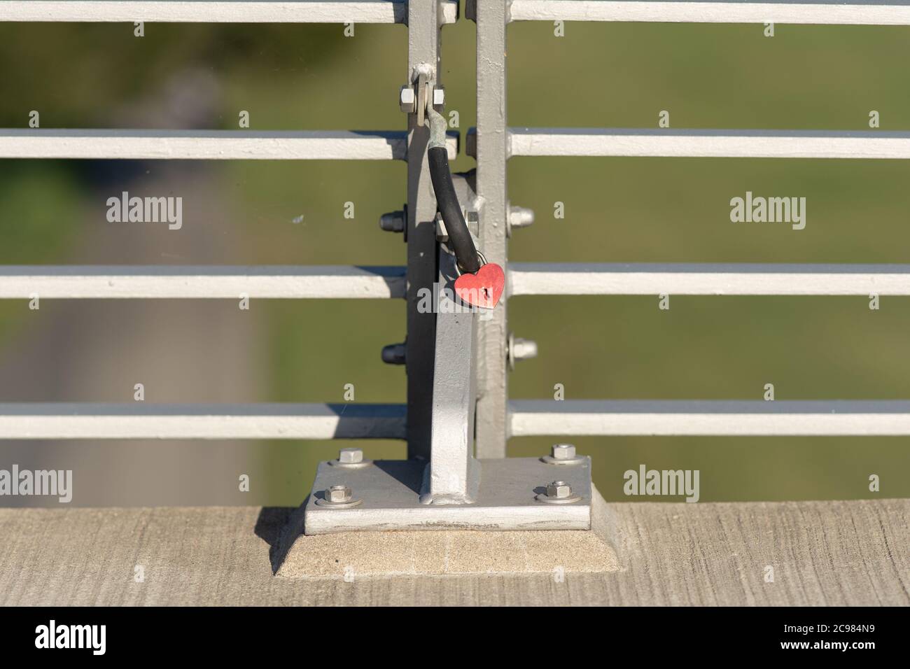 Red lock hanging on a bridge railing Stock Photo - Alamy