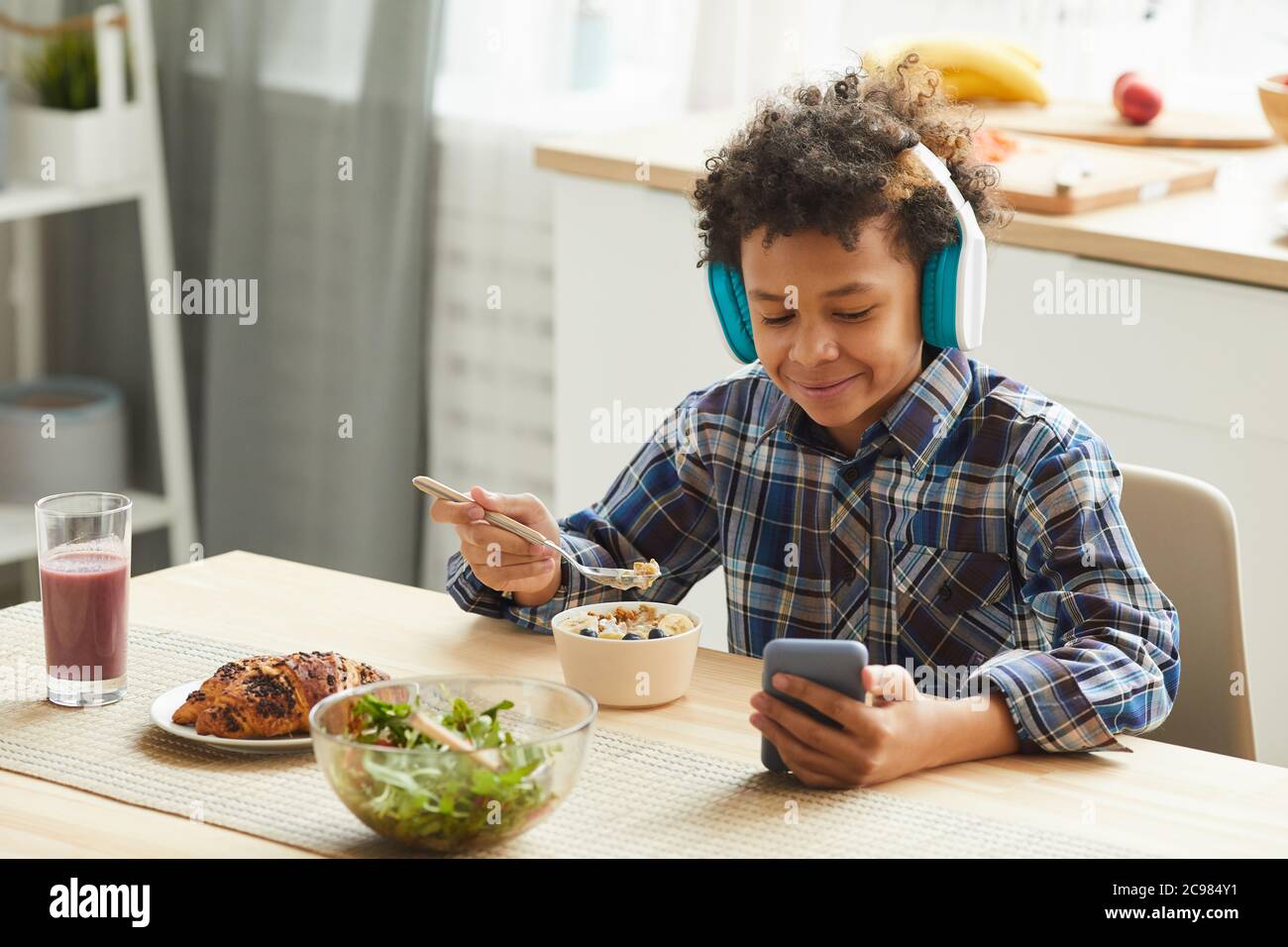African schoolboy wearing headphones watching online lessons on his ...