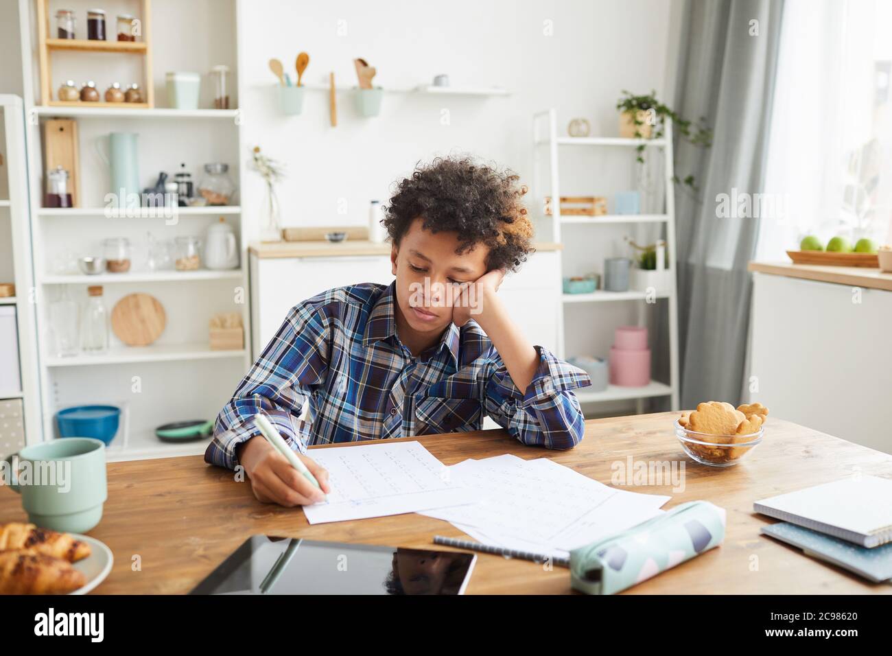 African boy writing in his notebook he doing his homework while sitting ...