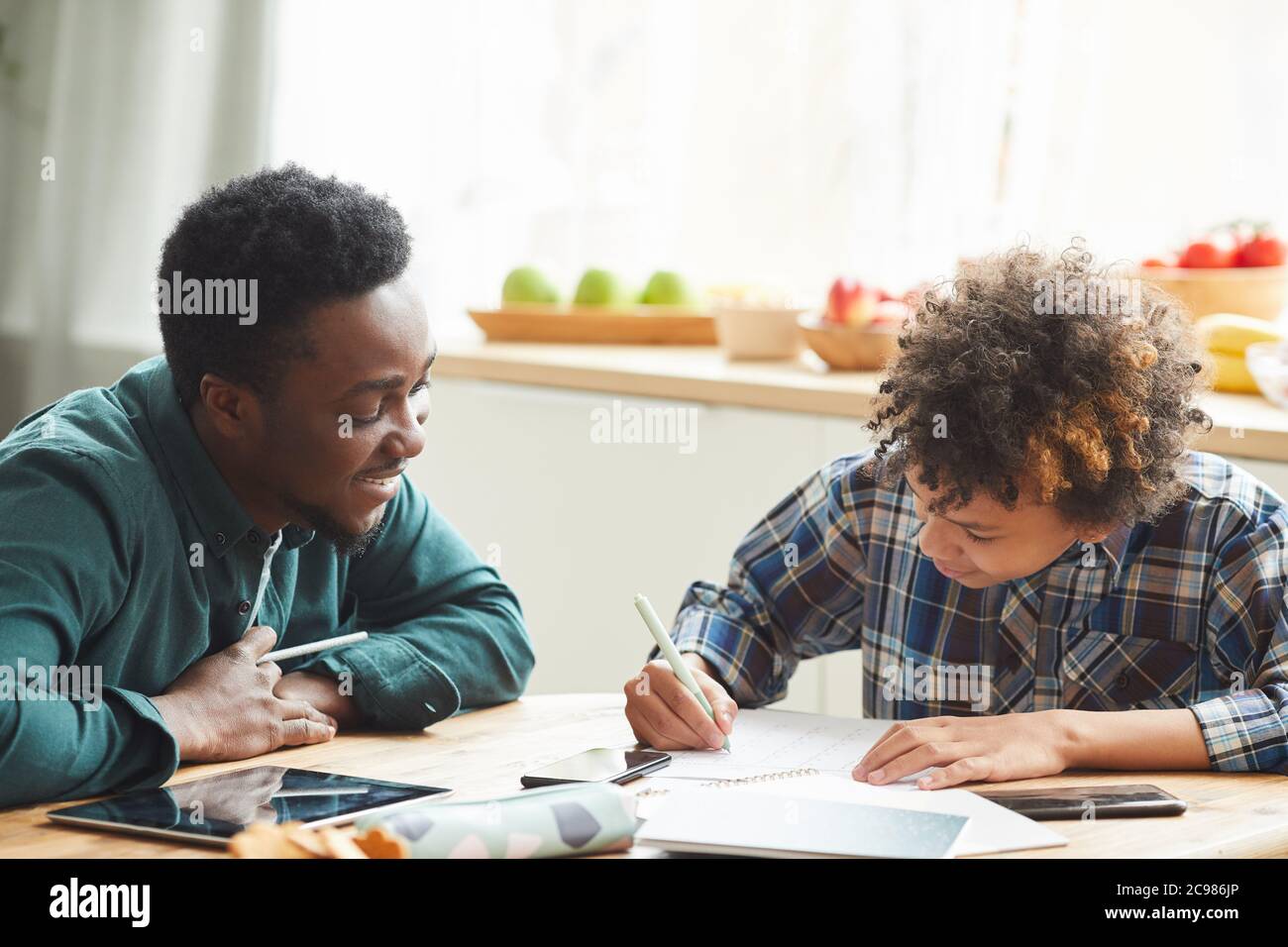 African father helping to his son to study during online education at ...