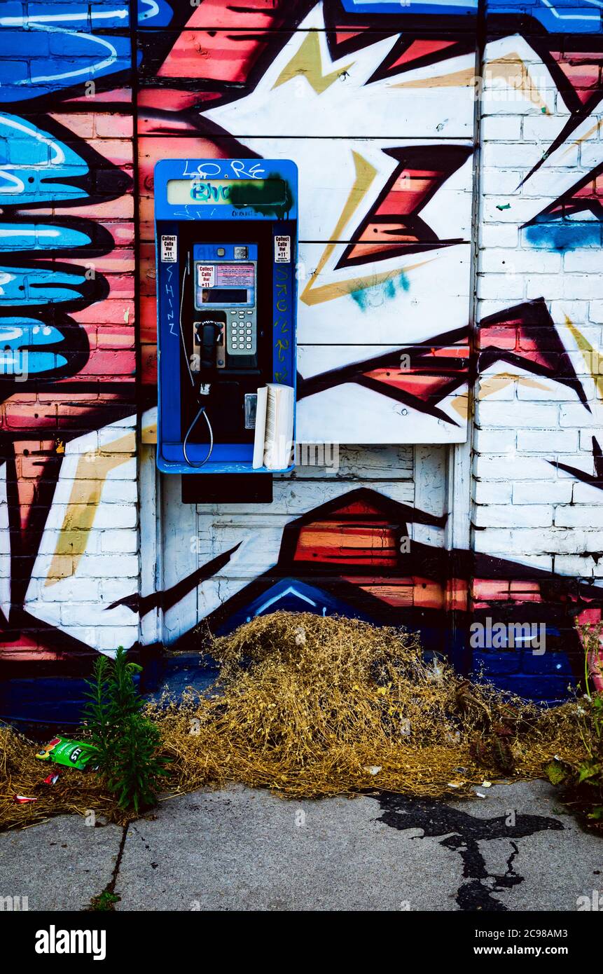 Outdoor telephone booth mounted on a graffiti painted wall Stock Photo ...