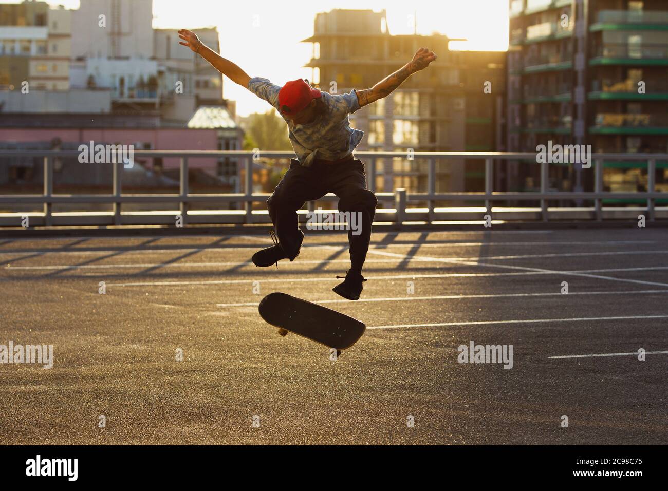 Skateboarder doing a trick at the city's street in summer's sunshine ...