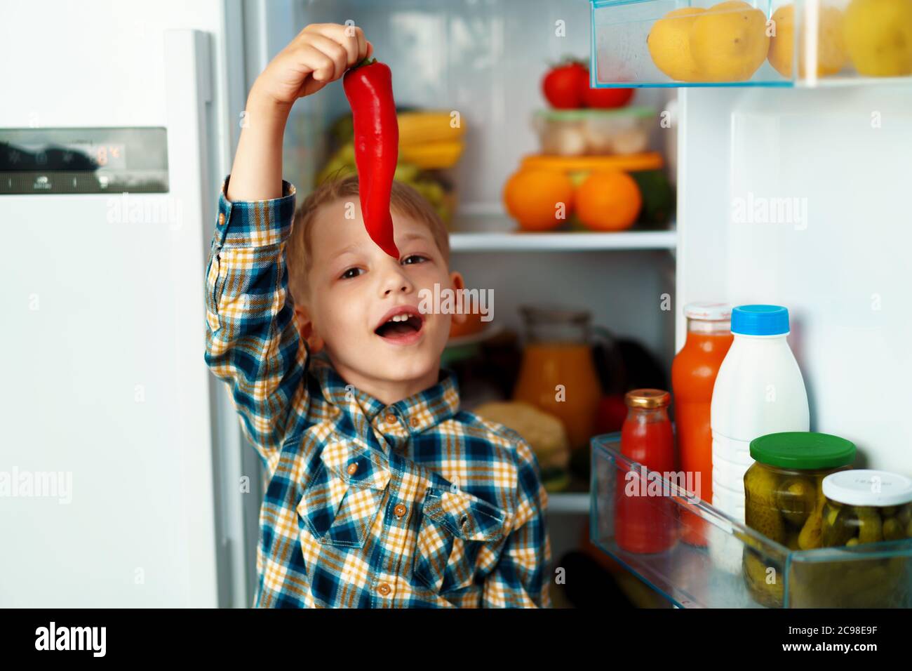 Little boy standing in front of open fridge and choosing food Stock ...