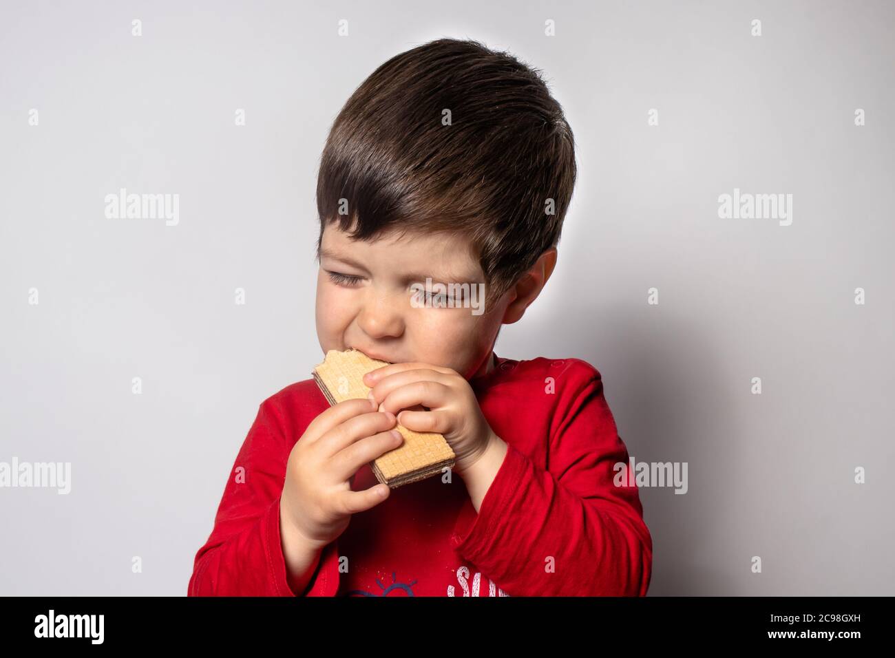 Little kid boy happily eats a crispy waffle. Happy baby and yummy Stock ...