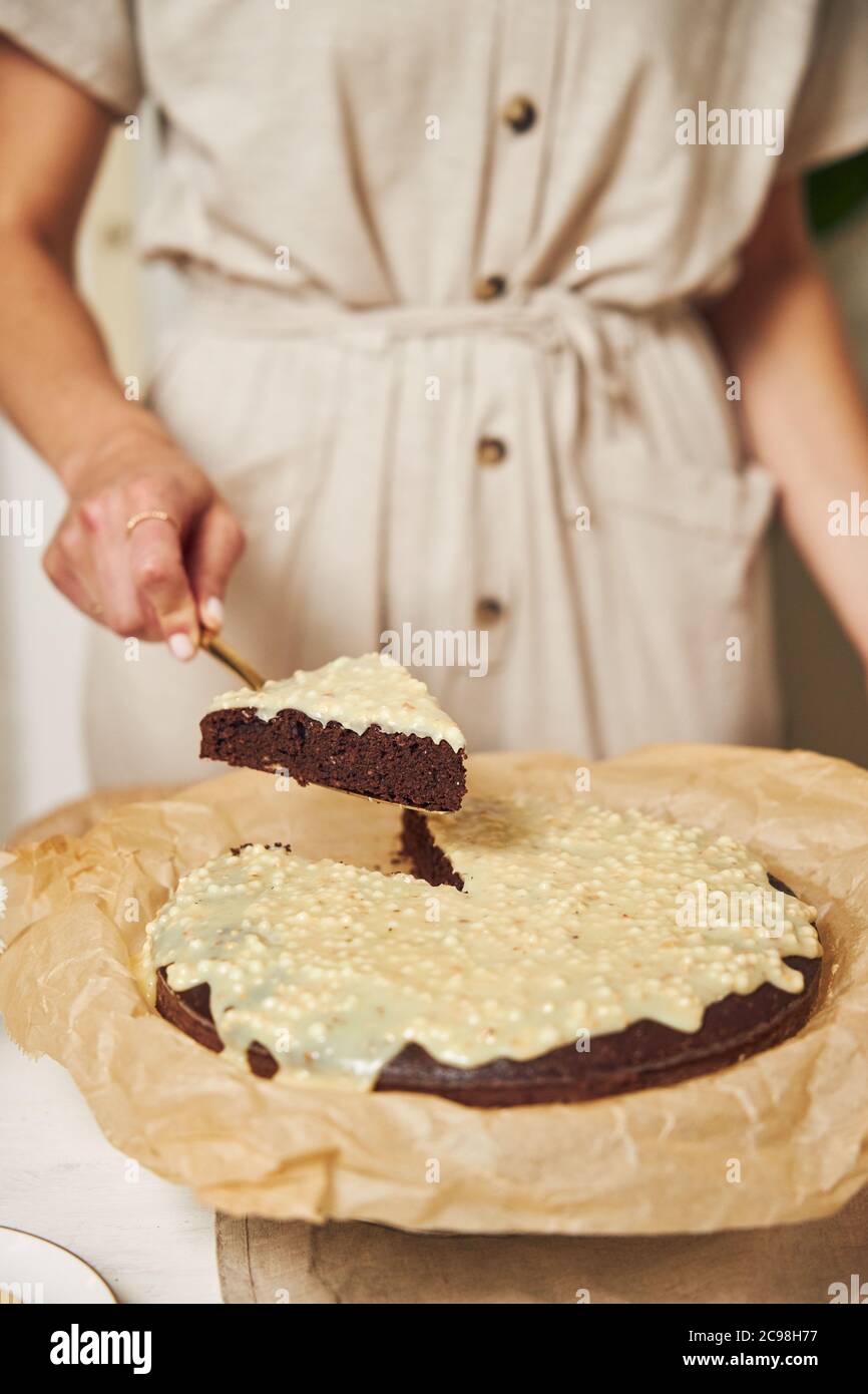 Young female cook making a delicious chocolate cake with cream on a ...