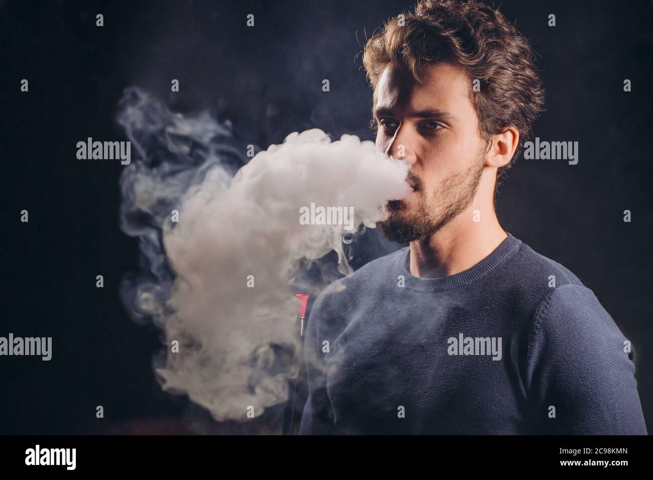 caucasian awesom man is blowing smoke. isolated on the black background ...