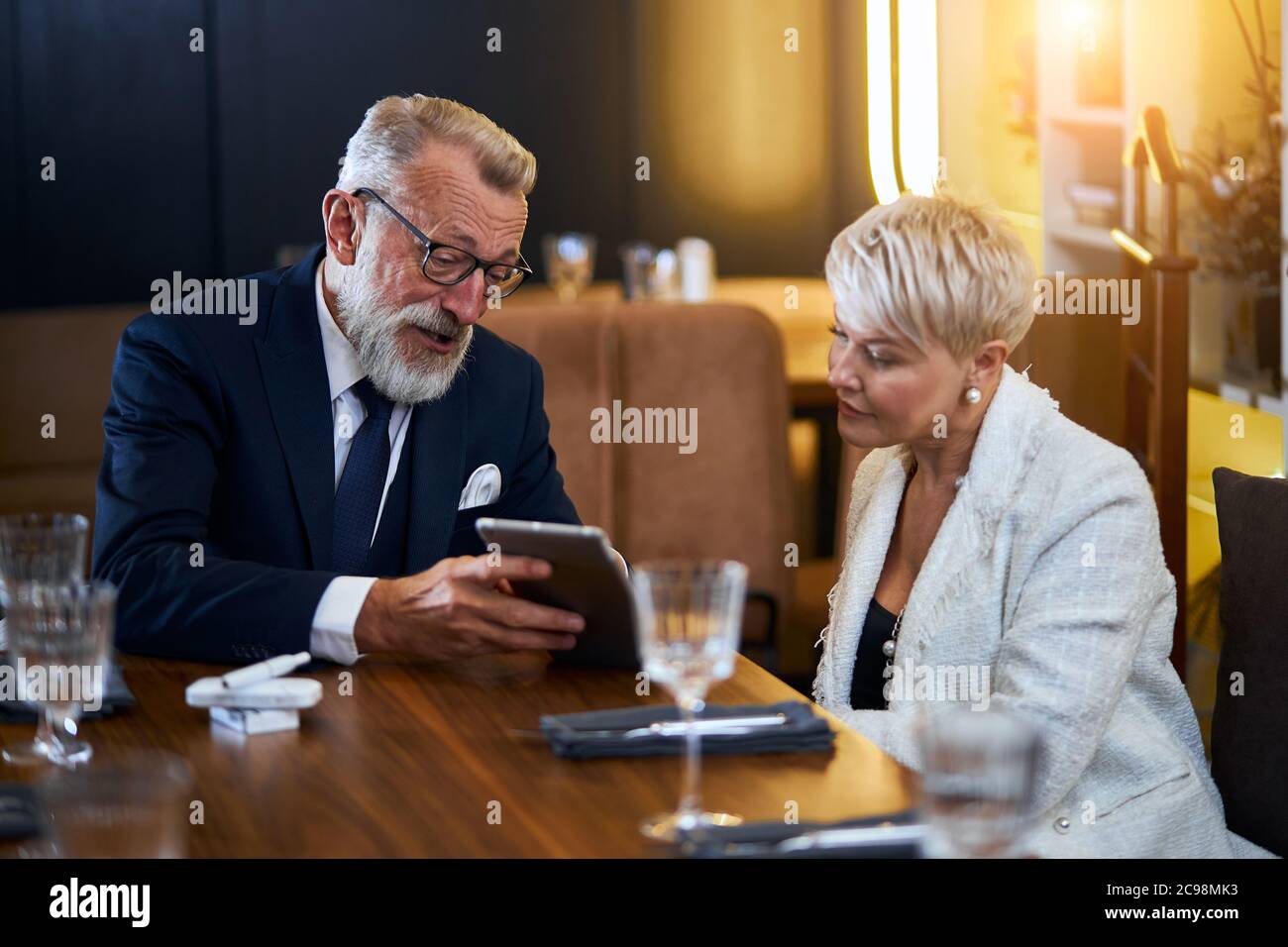 Beautiful senior couple in love speaking in rich restaurant, man show ...