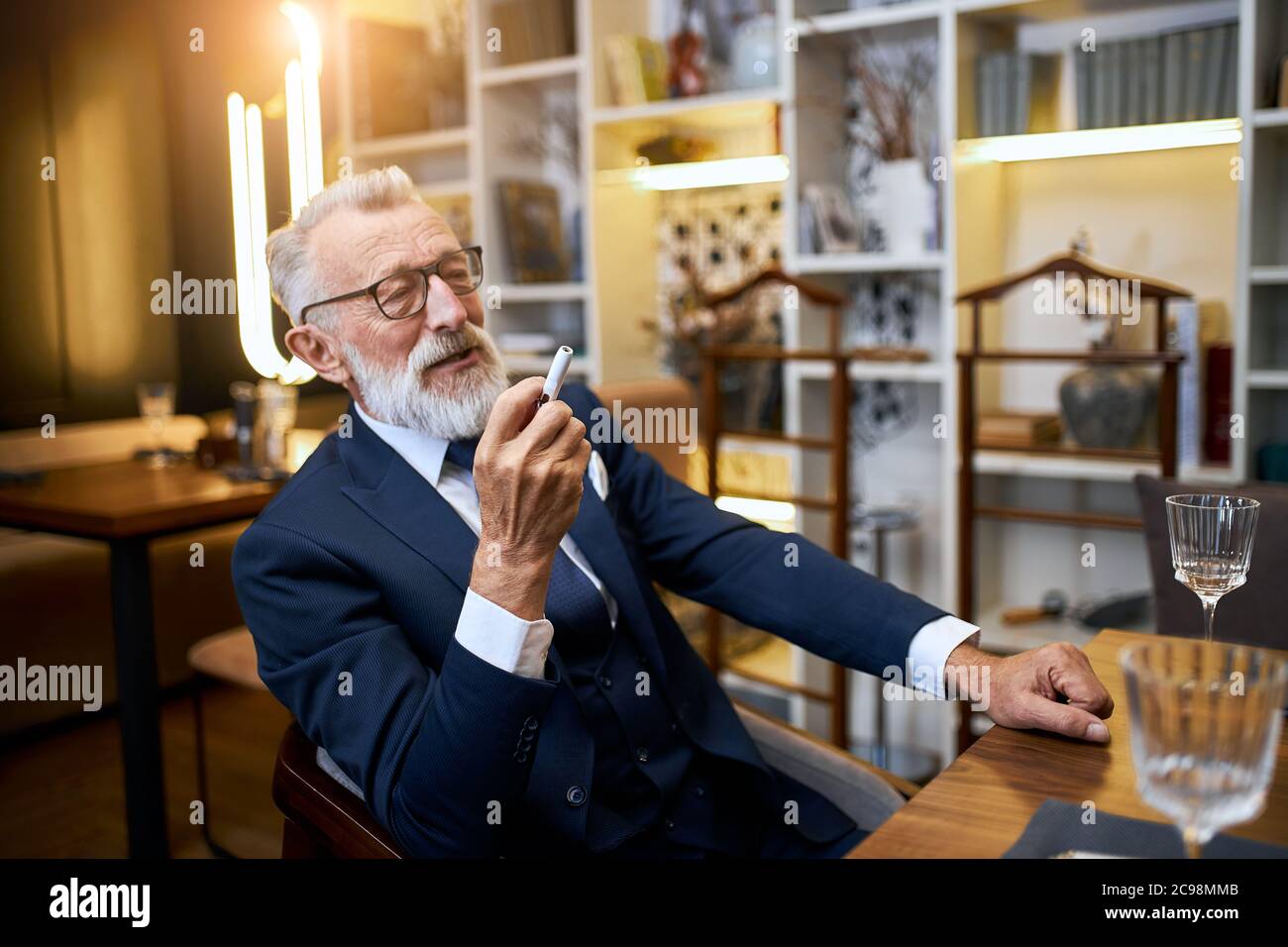 Attractive older man enjoys smoking electronic cigarette in restaurant ...
