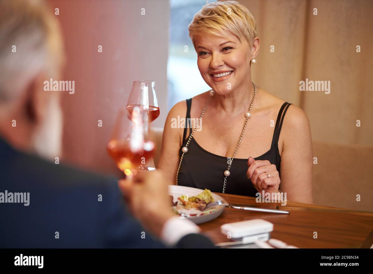 Caucasian senior woman in black dress fine dinner food with man in ...