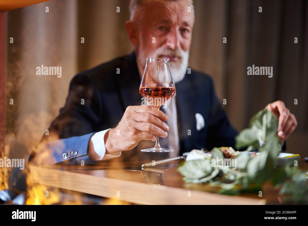 Mature beared businessman in tidy beautiful suit eat and drink ...