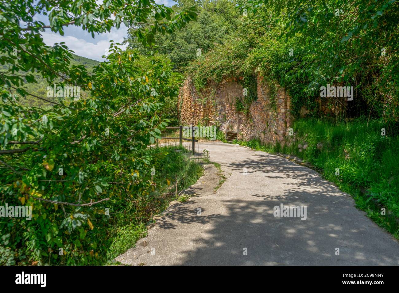 View of a nice country road with a stone wall, a wooden railing and ...