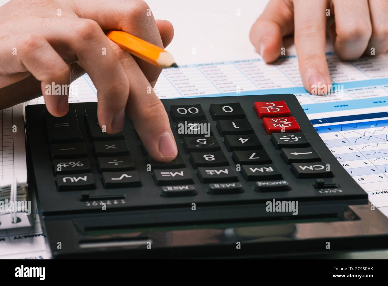 Calculator and hands with a pencil. Desktop with financial and ...
