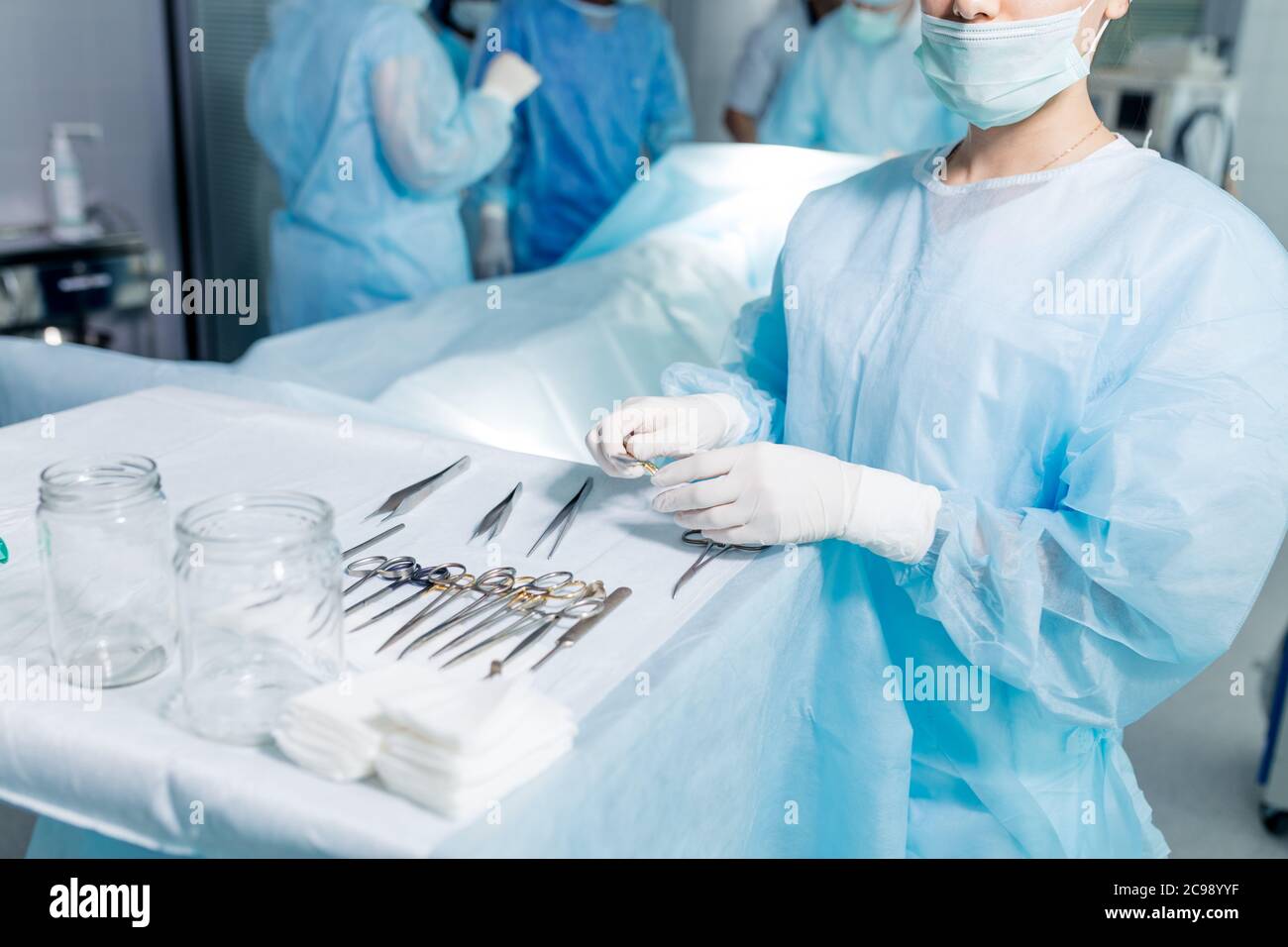 young doctor standing near the table full of different instrument ...