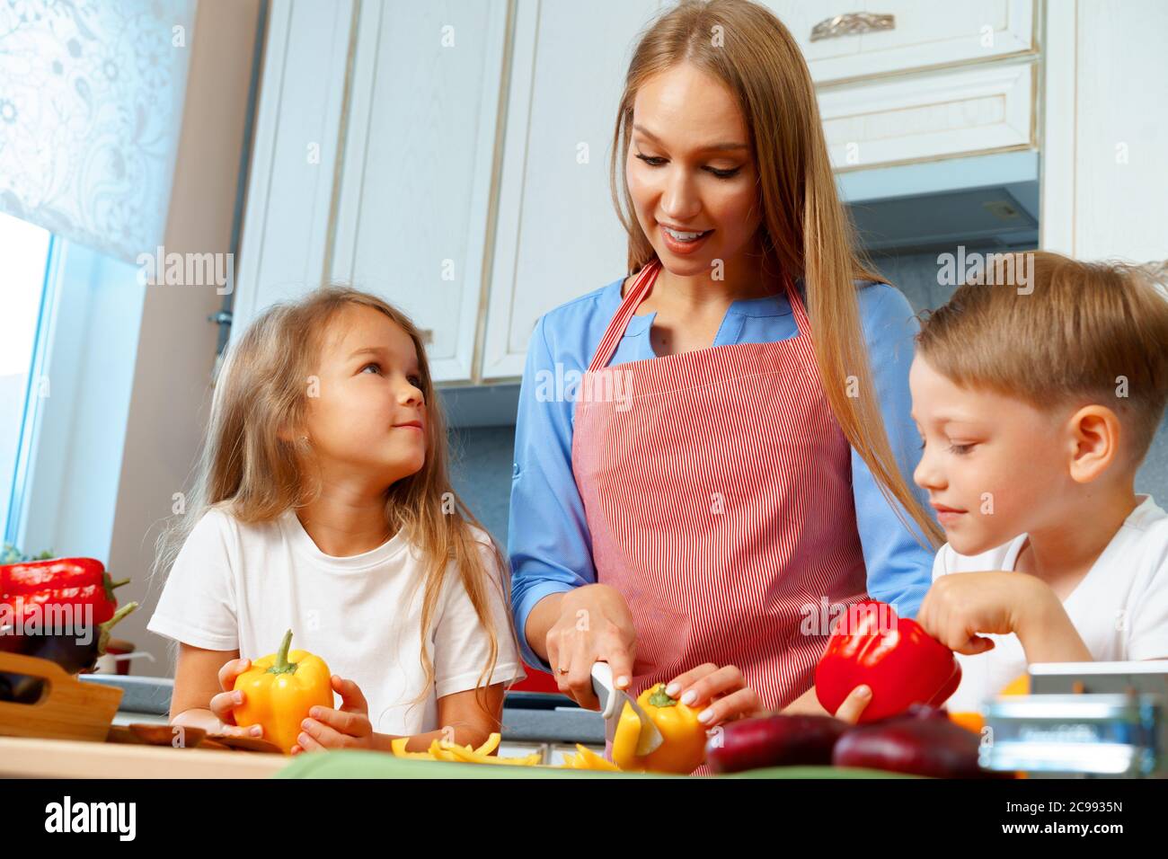 Mother cooking with her children in kitchen Stock Photo - Alamy