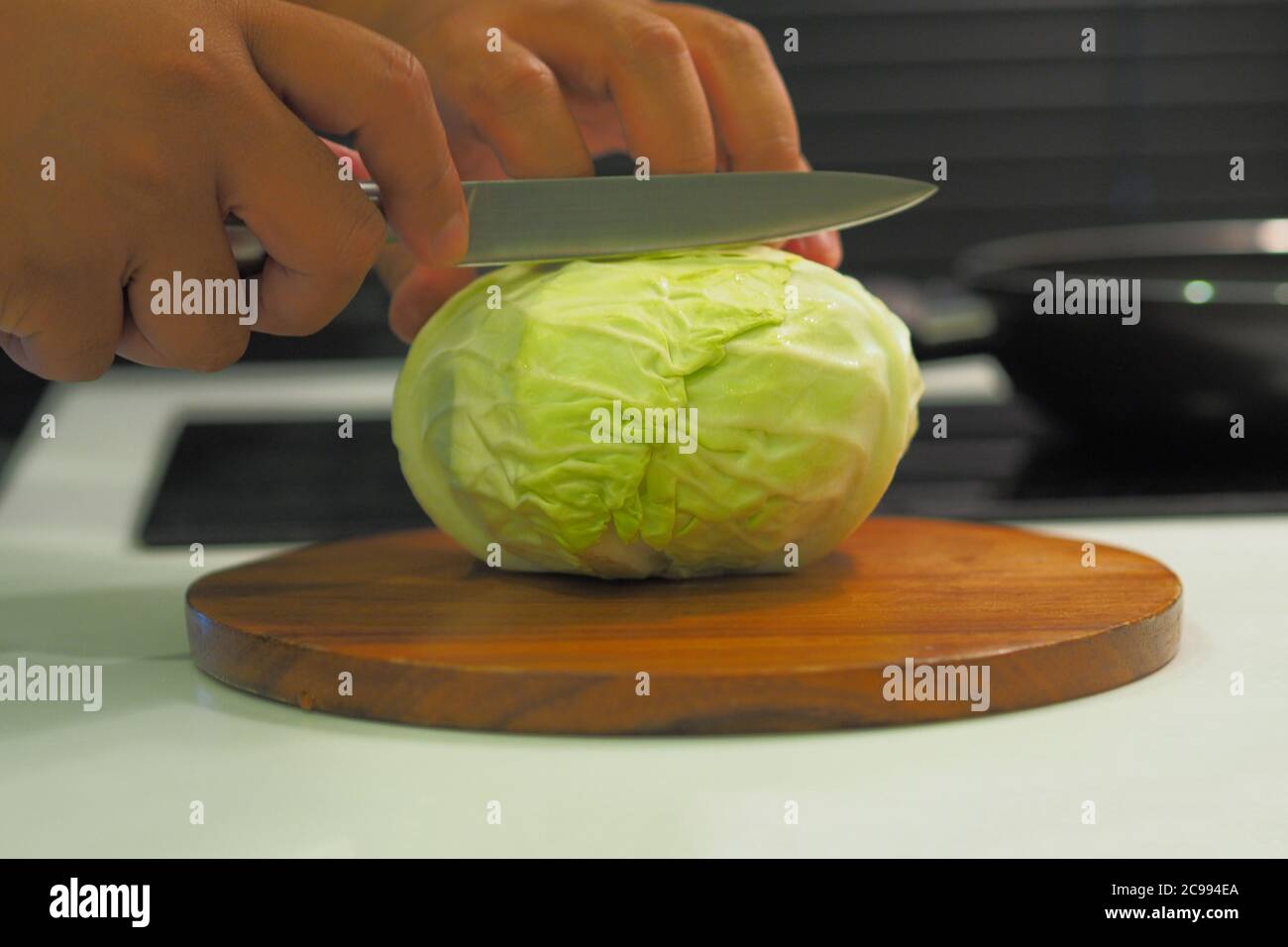The chef is facing the cabbage on the cutting board in the kitchen ...