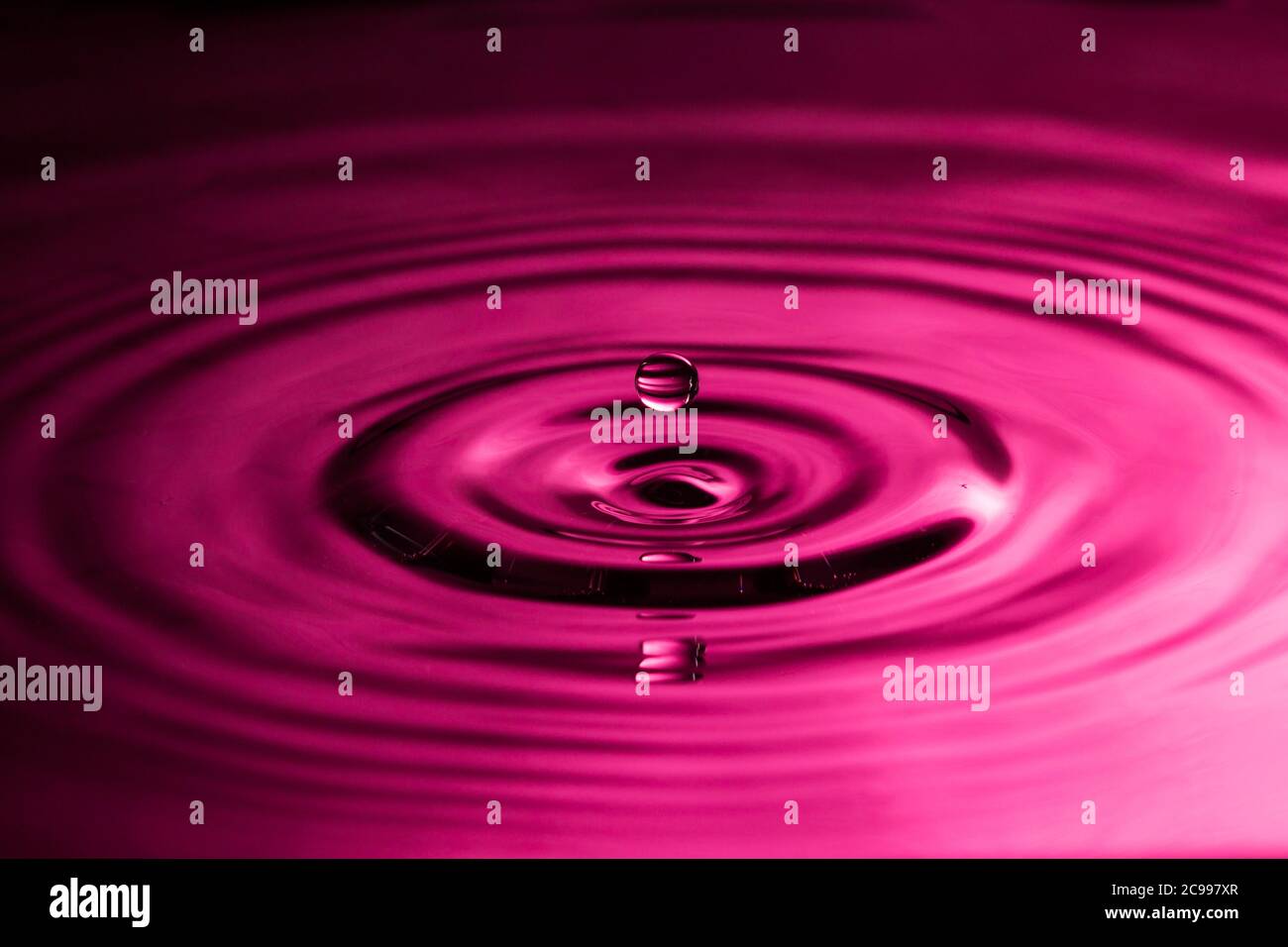 Perfect water drop splashing into smooth water causing ripples in a ...