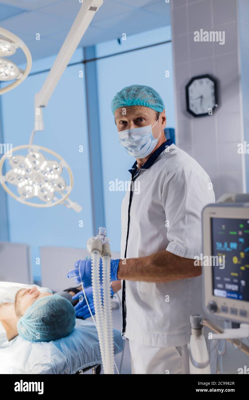 Caucasian Surgeon standing with artificial ventilation hose and looking ...