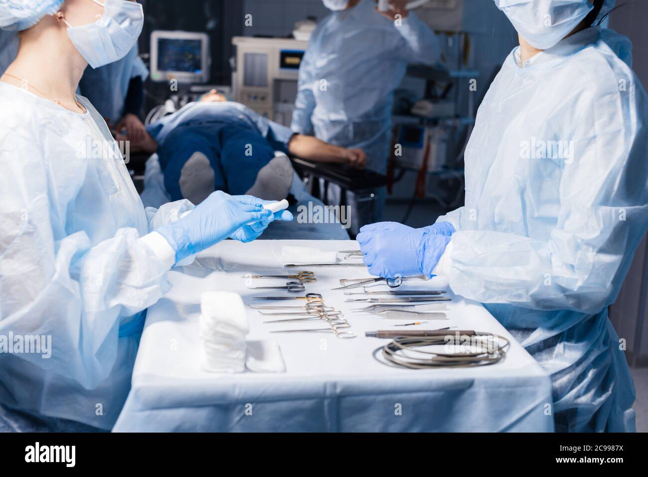 Two diverse female nurses taking surgical instrument for group of ...