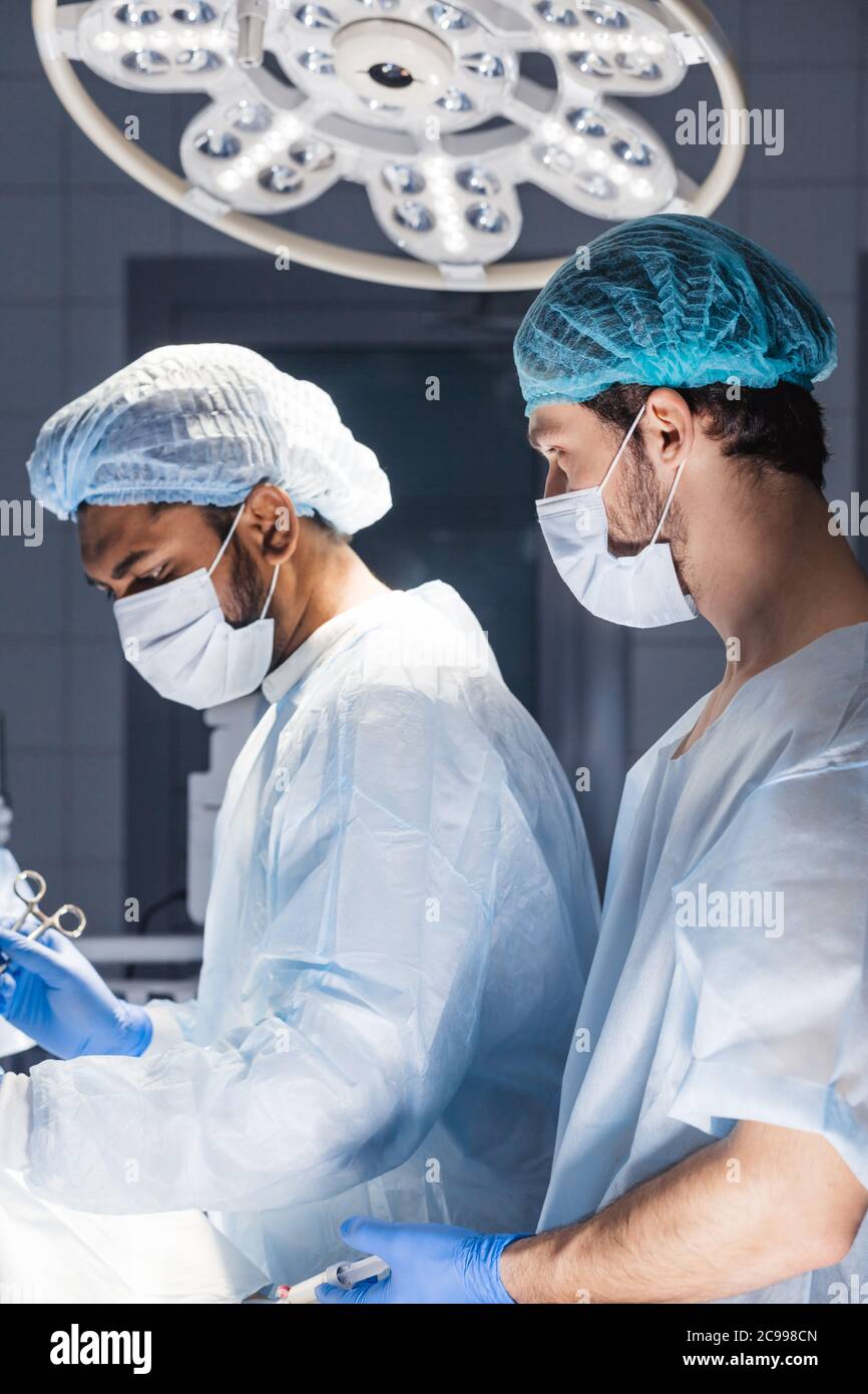 Diverse team of professional surgeons performing invasive surgery on a ...