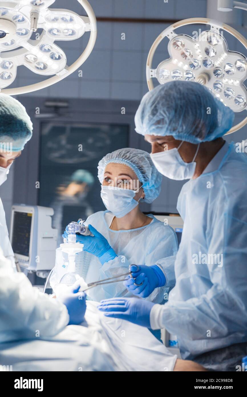 Group of concentrated surgeons engaging in rescue of male patient in ...