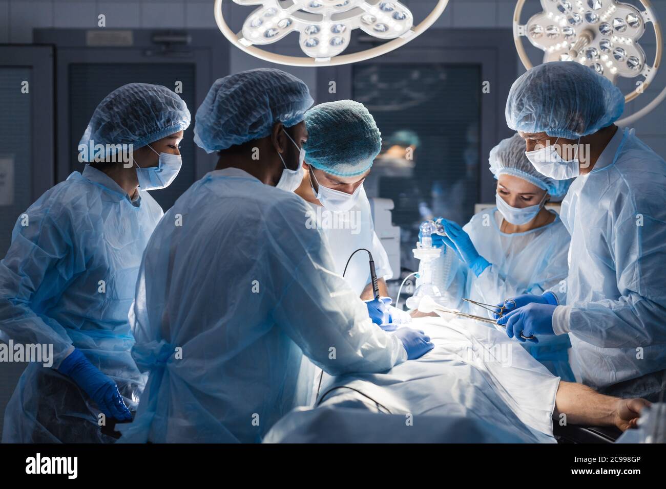 Group of concentrated surgeons engaging in rescue of male patient in ...
