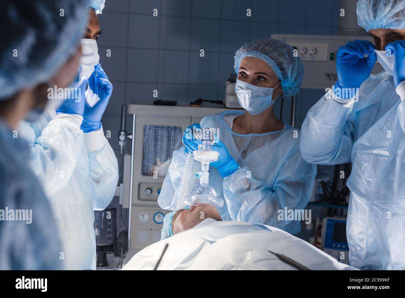 Female nurses putting oxygen mask on patient in operation room. Jaw ...