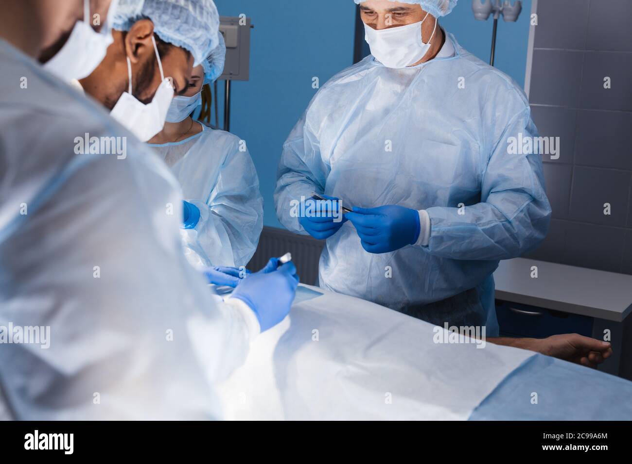 Diverse team of professional surgeons performing invasive surgery on a ...