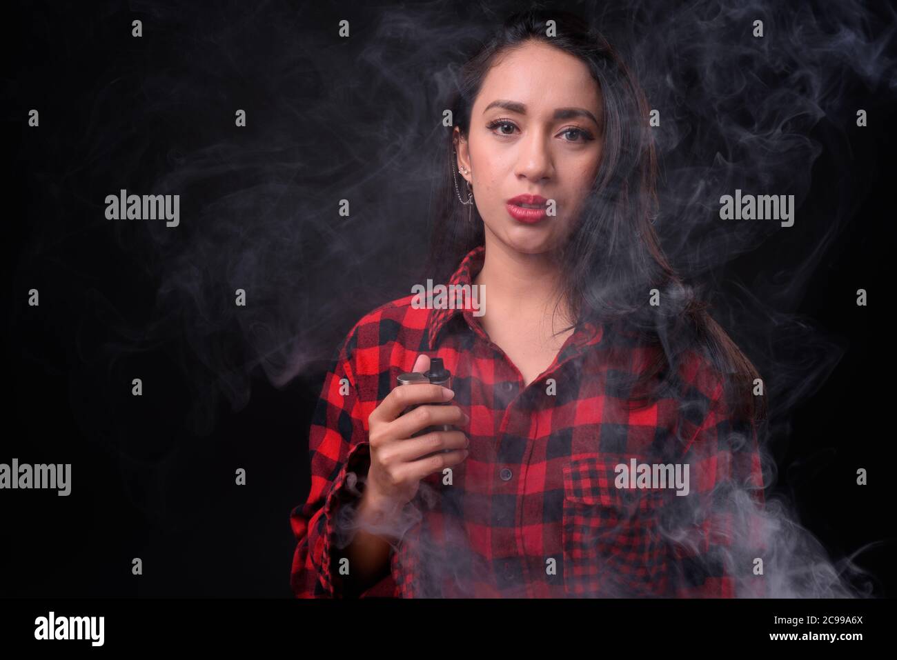 Young beautiful Asian woman vaping against black background Stock Photo ...