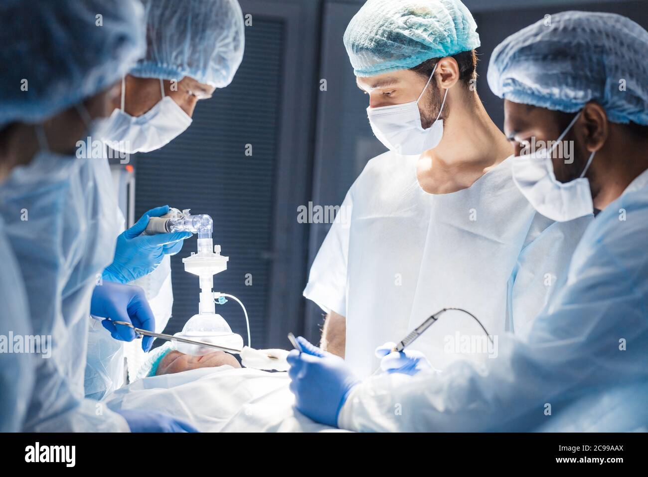 Diverse team of professional surgeons performing invasive surgery on a ...