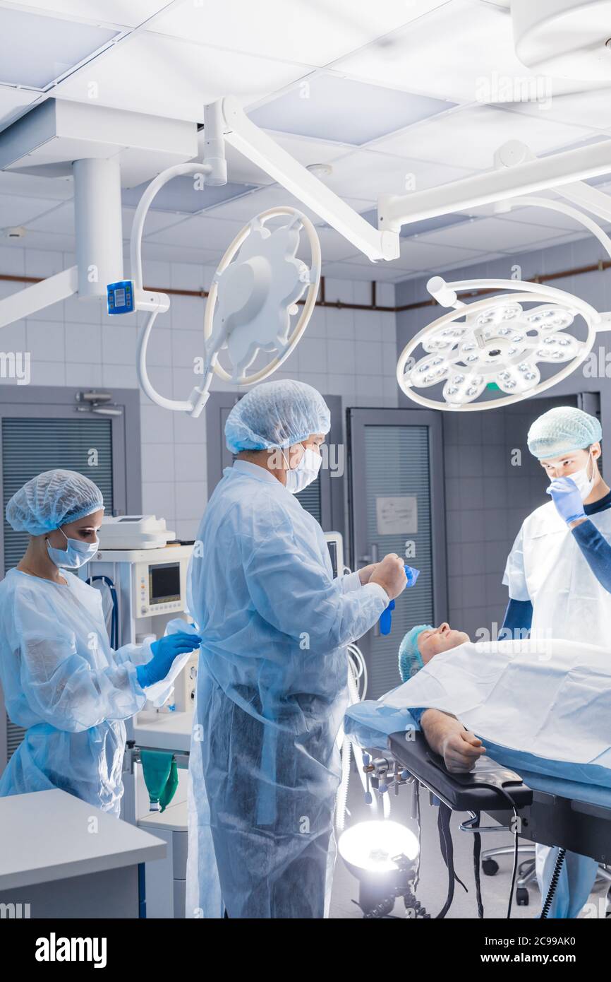 Surgery preparations. Surgical team preparing their patient for surgery ...