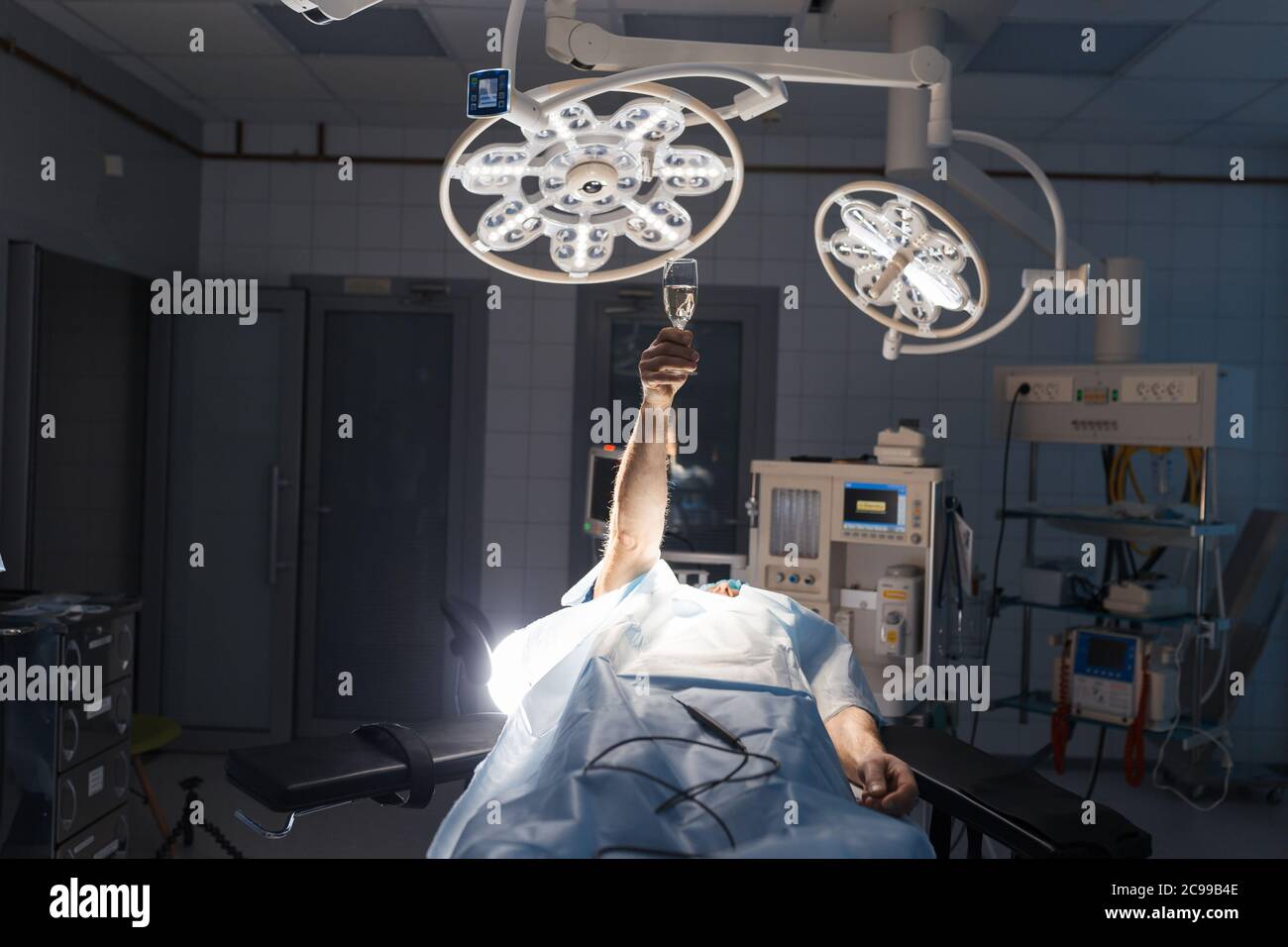 Ironic picture of patient on surgery couch raises up the hand with ...