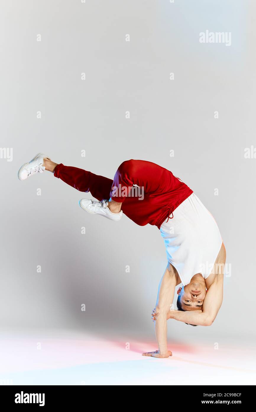 Stylish dressed in red sweatpants asian b-boy is performing kick in air ...