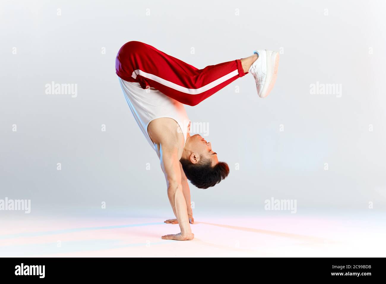 Free style dancer in red sports trousers doing some acrobatic stunts ...