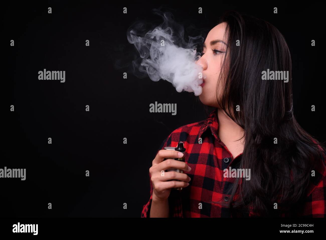 Young beautiful Asian woman vaping against black background Stock Photo ...