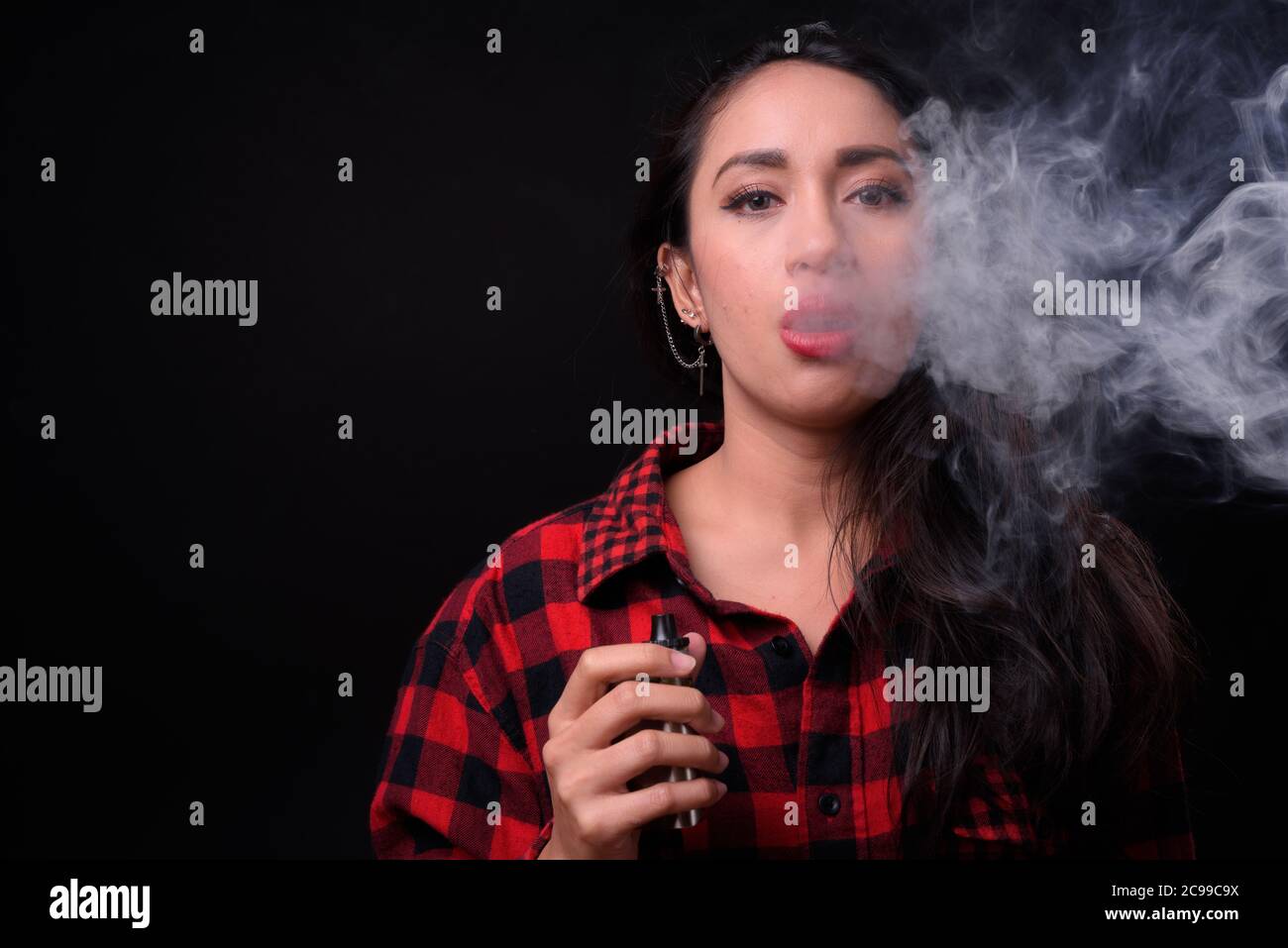 Young beautiful Asian woman vaping against black background Stock Photo ...