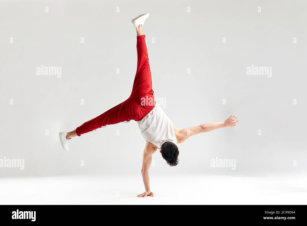 Break dancer doing handstand stunt on one hand and splitted out legs ...