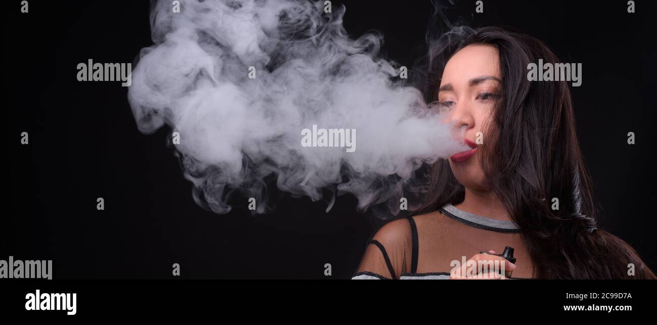 Young beautiful Asian woman vaping against black background Stock Photo ...