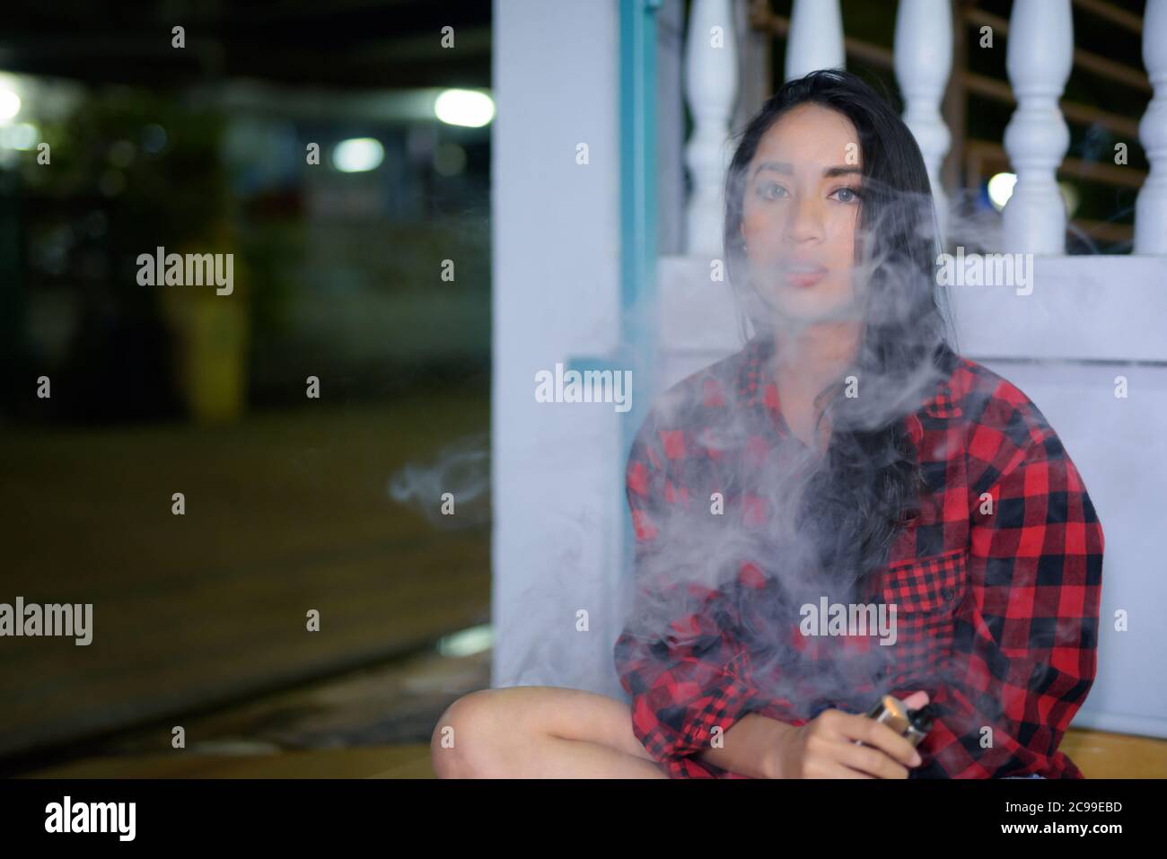 Young beautiful Asian woman vaping at home outdoors Stock Photo - Alamy